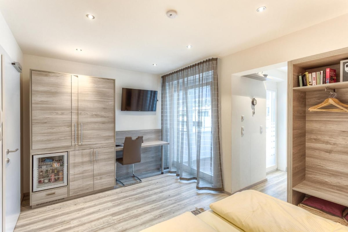Quarto moderno com guarda-roupa, escrivaninha e televisão.