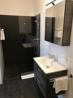 Casa de banho moderna com cabine de hidromassagem, toucador com lavatório e espelho.