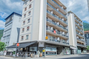 Um hotel com vários andares, varandas, um café no andar térreo e uma placa com a inscrição Garni Moderno Rooms.