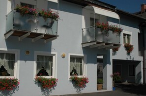 Um edifício com várias varandas, cada uma delas decorada com floreiras cheias de flores vermelhas e cor-de-rosa.