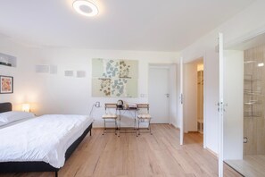 Quarto com cama, escrivaninha, cadeiras, máquina de café e guarda-roupa.