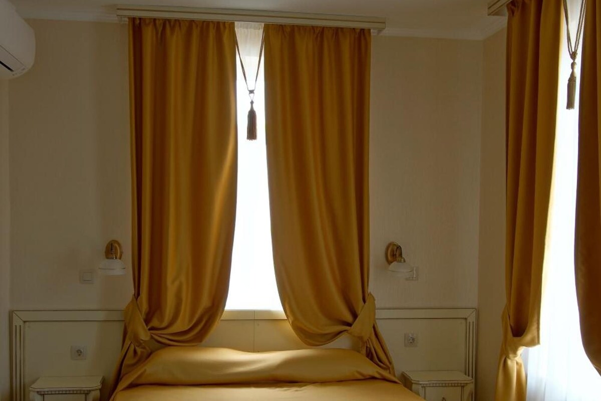 Quarto com cama grande, duas mesas de cabeceira e cortinas.