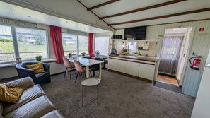 Quarto compacto com mesa de jantar, cadeiras, sofá e pequeno espaço de cozinha.