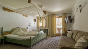 Quarto com cama, sofá, televisão e janela com cortinas.
