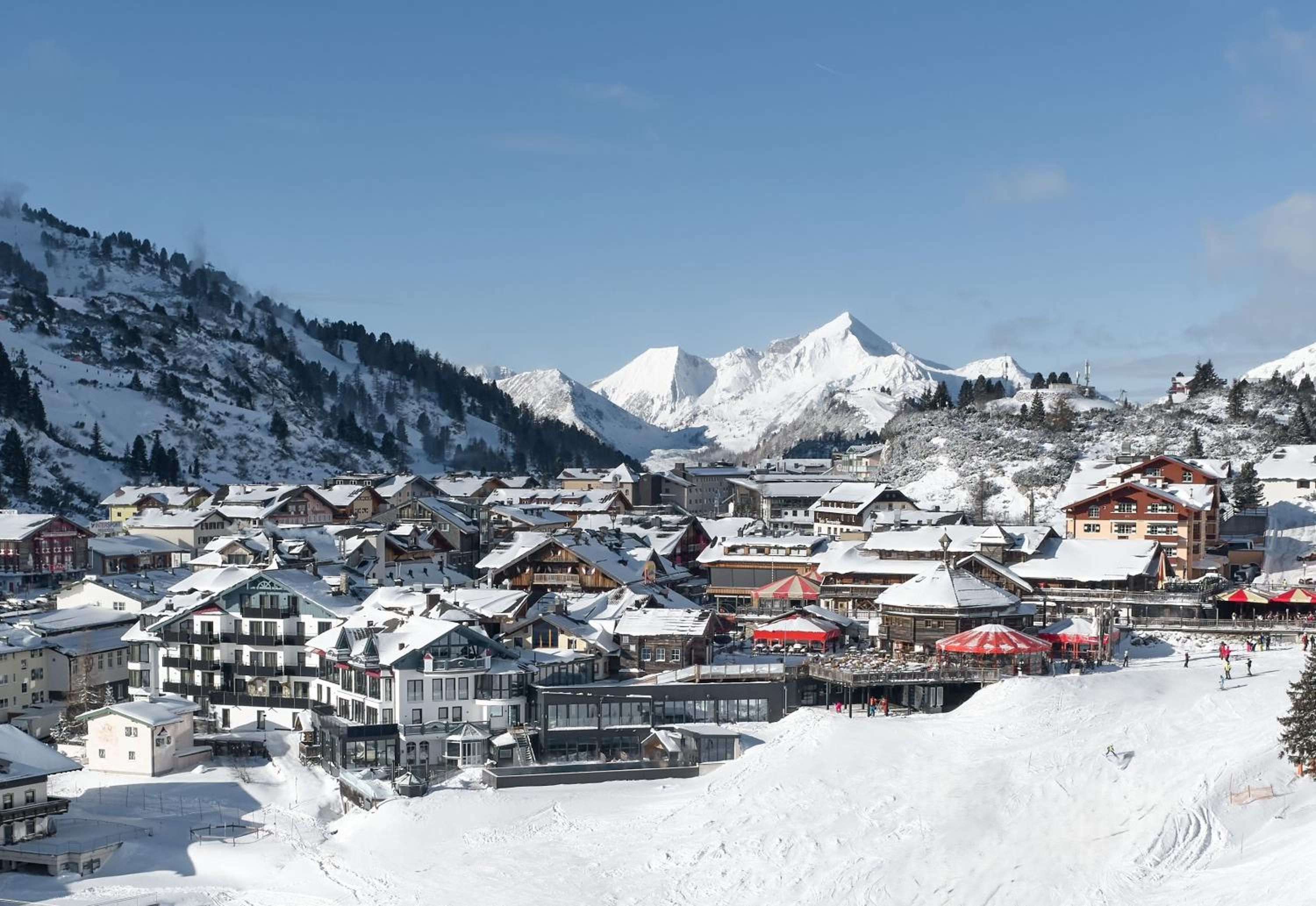 Cidade montanhosa coberta de neve, com edifícios e pista de esqui.