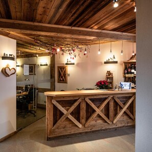Interior rústico com balcão de recepção de madeira, luminárias pendentes e placa na parede.