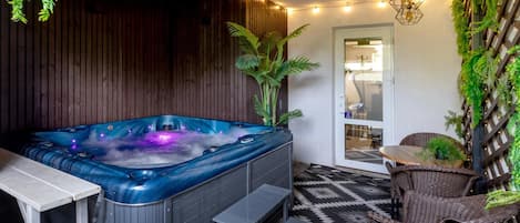 Uma banheira de hidromassagem com interior azul, rodeada por paredes de madeira e um piso estampado.