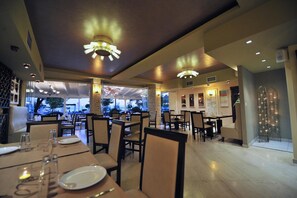 Restaurante com várias mesas e cadeiras, vista para o exterior e design de interiores moderno.