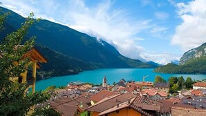 Uma cidade com arquitetura tradicional, um lago e montanhas ao fundo.