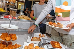 Disposição de buffet com diversos alimentos, incluindo doces e um bolo.