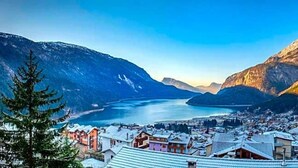 Paisagem montanhosa com um lago, edifícios cobertos de neve e céu limpo.