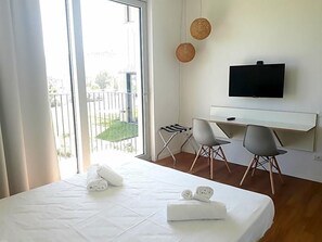 Quarto de hotel com cama, escrivaninha, televisão e vista para o exterior.