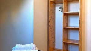 Quarto com uma cama, um guarda-roupa de madeira e uma toalha dobrada no chão.