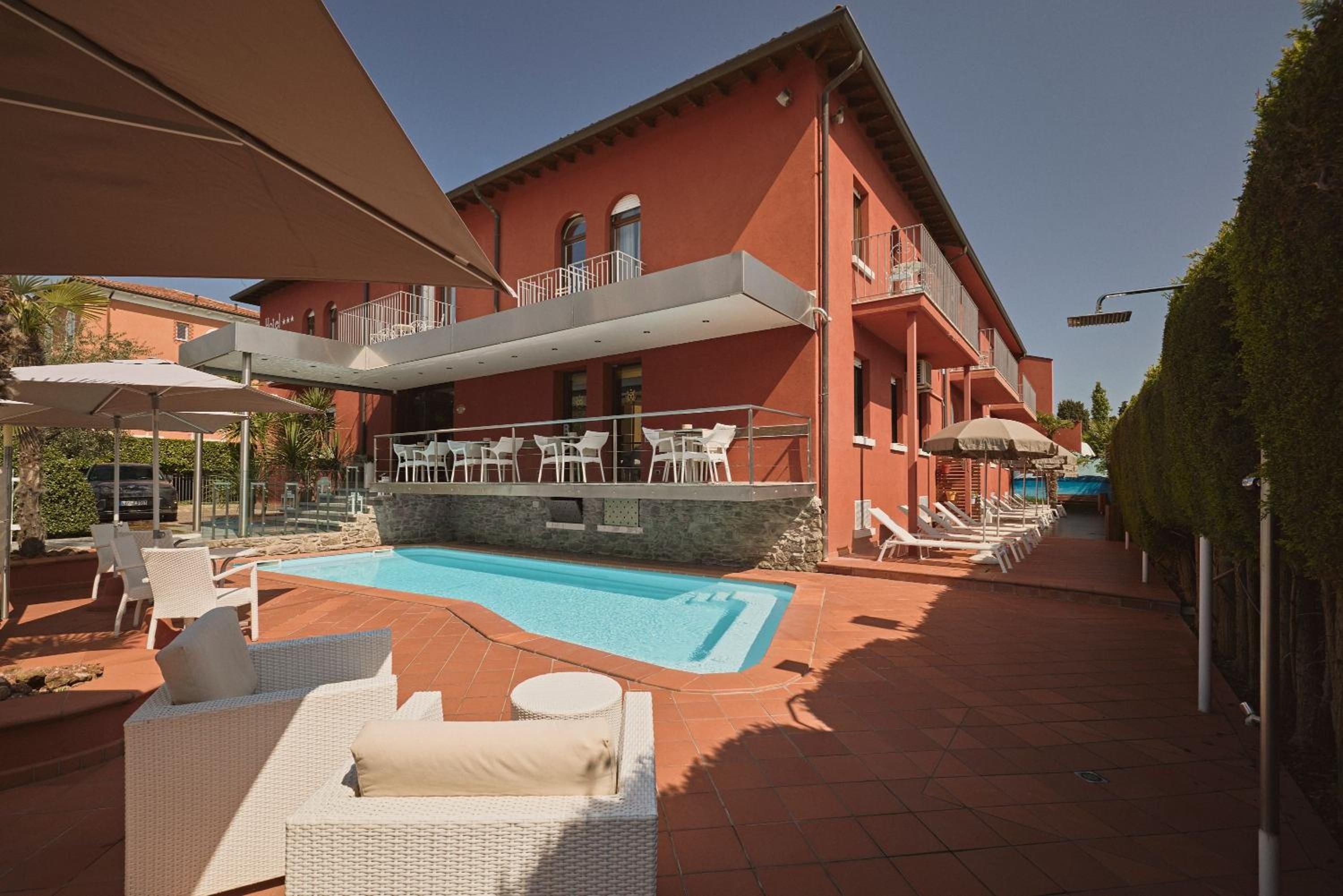 Hotel com piscina, área de estar externa e fachada vermelha.