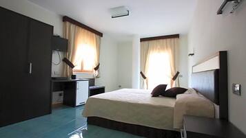 Um quarto com cama, escrivaninha e guarda-roupa.