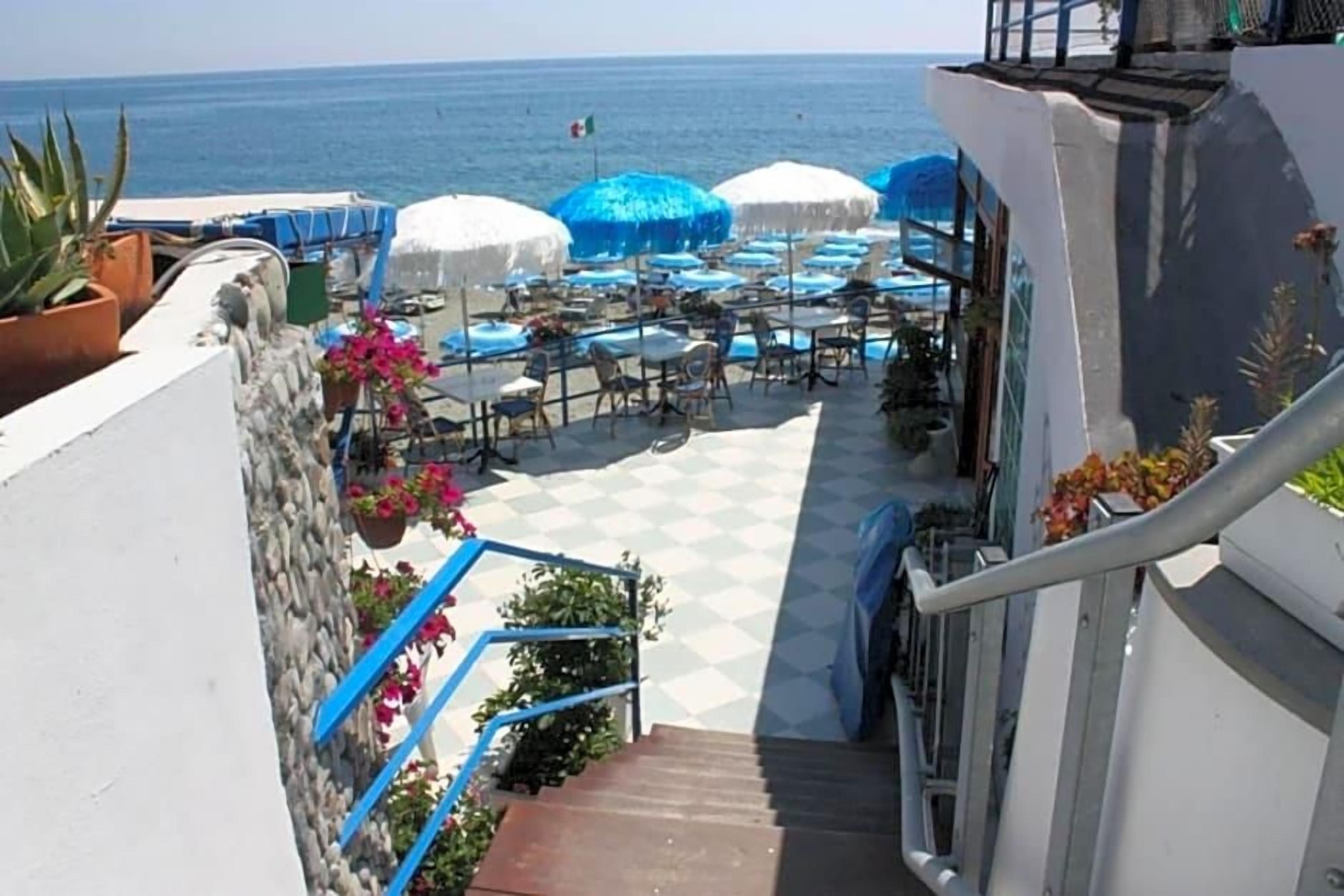 Terraço com área de estar externa, escada e vista para o mar.