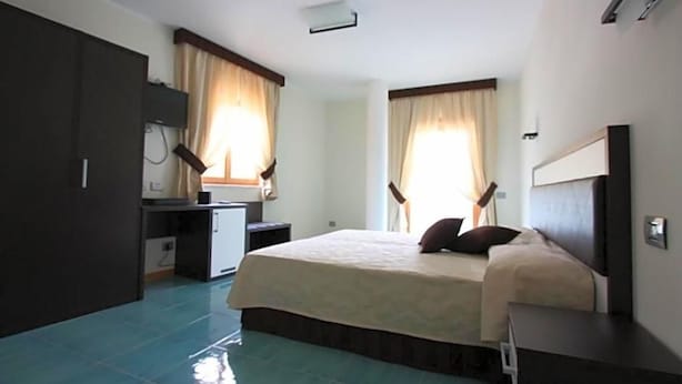 Um quarto com cama, escrivaninha e guarda-roupa.