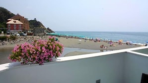 Uma praia com pessoas, guarda-sóis e um edifício ao fundo.