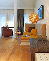 Quarto de hotel moderno com cama, área de estar e televisão.
