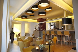Um interior moderno com área de bar, assentos e escadaria para um andar superior.