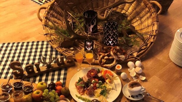Uma mesa de madeira com diversos alimentos, incluindo frutas, pão e um prato de aperitivos.