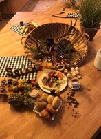 Uma mesa de madeira com diversos alimentos, incluindo frutas, pão e um prato de aperitivos.