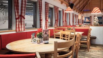 Um restaurante com mobiliário de madeira, almofadas vermelhas e vista para uma área externa.