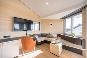 Uma sala de estar moderna com televisão de tela plana, sofá, mesa de centro e uma poltrona.
