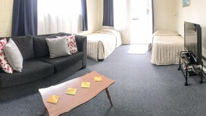 Sala de estar com sofá, mesa de centro, televisão e cama.