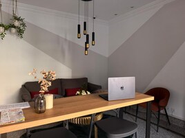Uma sala de jantar moderna com mesa de madeira, um laptop e um sofá.