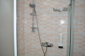 Chuveiro com chuveiro manual, torneira fixada na parede e mangueira de chuveiro.