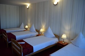 Quarto de hotel com duas camas de solteiro, cada uma com mesa de cabeceira e luminária, e uma cadeira de madeira.