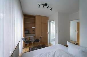 Quarto com cama, escrivaninha, cadeira, guarda-roupa e chuveiro.