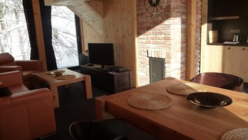 Quarto aconchegante com lareira, móveis de madeira e televisão.