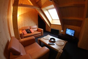 Um quarto acolhedor no estilo loft, com decoração em madeira, um sofá, uma mesa de centro e uma televisão.