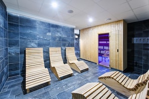 Uma área de sauna com espreguiçadeiras de madeira e parede de madeira.