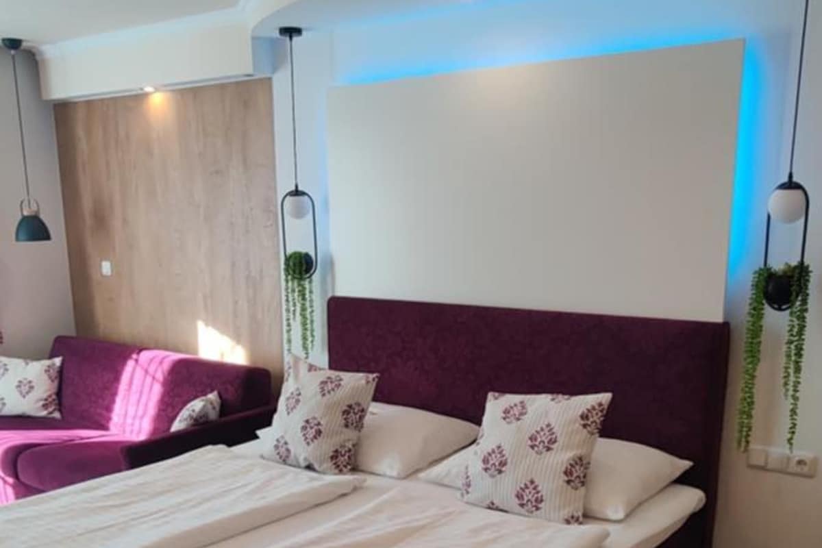 Quarto moderno com uma cama grande, um sofá e plantas penduradas.