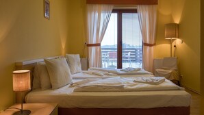 Quarto de hotel com cama, abajures, janela com cortinas e vista para a cidade.