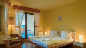 Quarto de hotel com cama, mesas de cabeceira, uma cadeira e vista para o exterior.