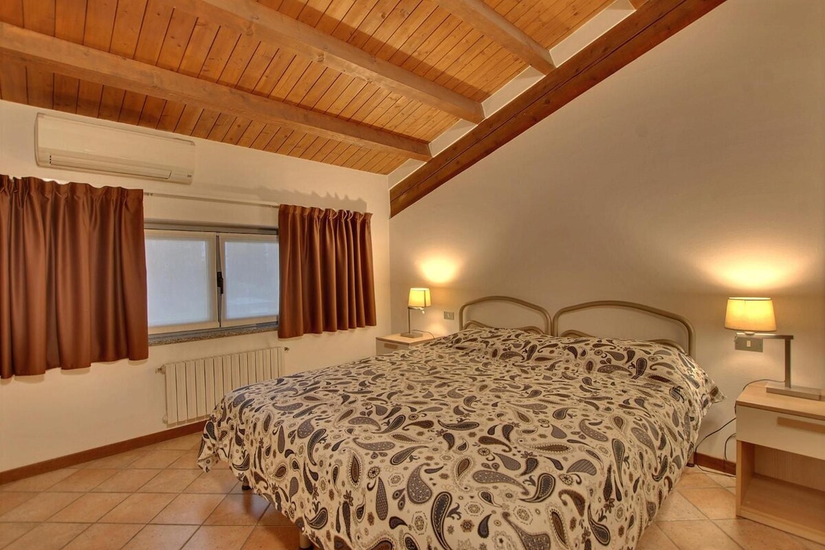 Quarto com cama, cortinas, janela e abajures.