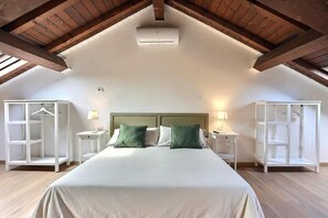 Quarto com uma cama grande, duas mesas de cabeceira, um guarda-roupa e um ventilador de teto.