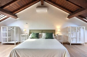 Quarto com uma cama grande, duas mesas de cabeceira, um guarda-roupa e um ventilador de teto.