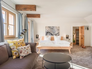 Quarto com cama, sofá, mesa de centro e um quadro na parede.
