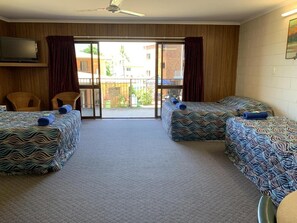 Quarto com duas camas, ventoinha no teto e vista para o exterior.