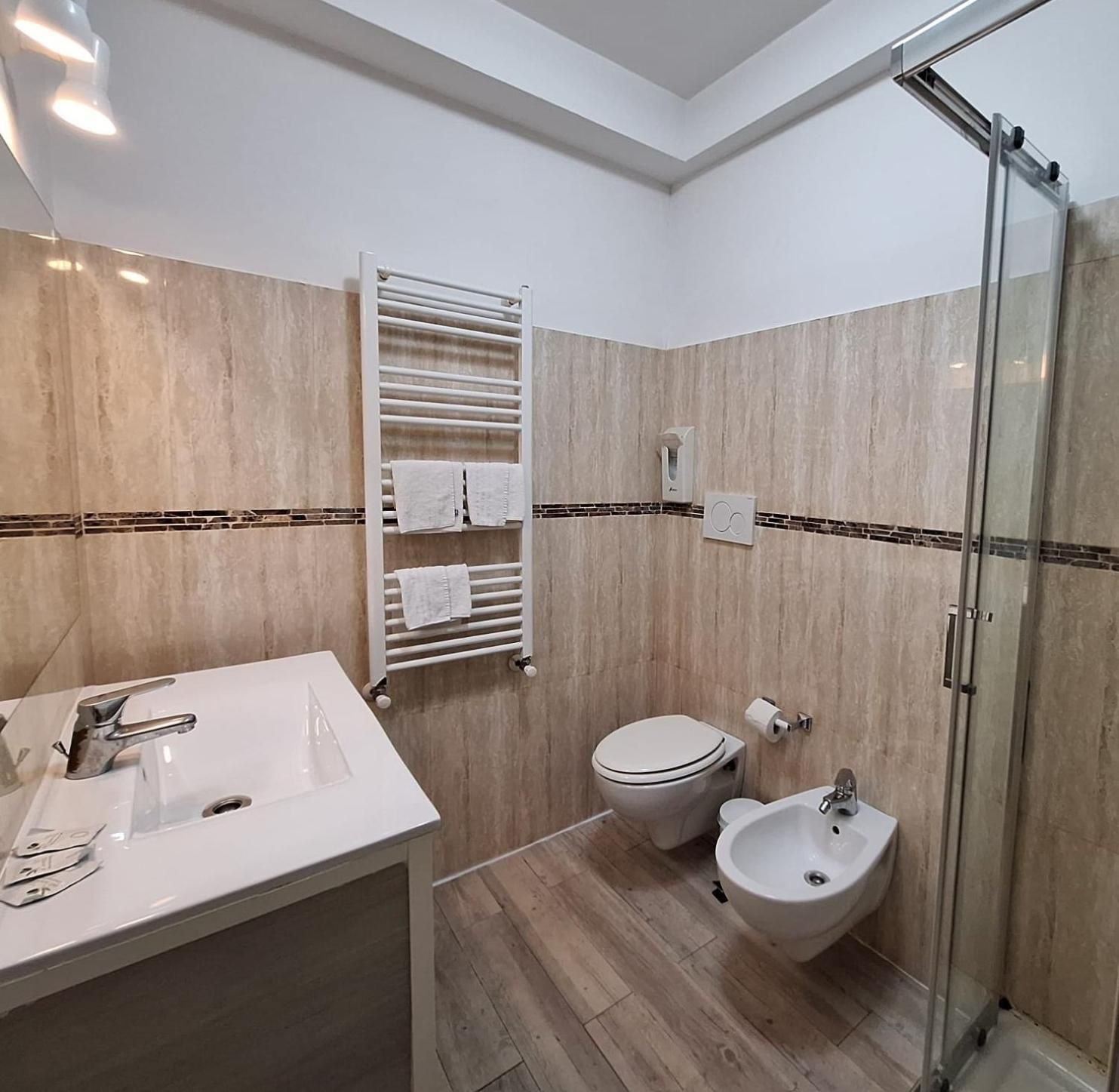Uma casa de banho moderna com lavatório branco, sanita, bidé e cabine de duche em vidro.