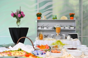Disposição de buffet com diversos alimentos e uma parede decorativa com padrão de ondas.