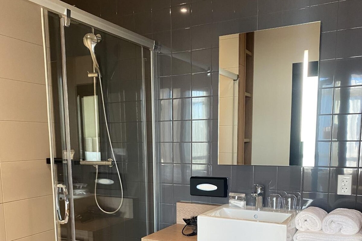 Uma casa de banho moderna com cabine de chuveiro em vidro, toucador com lavatório e espelho.