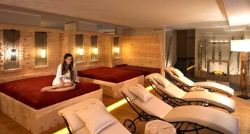 Um espaço de spa com paredes de madeira, várias camas e uma lareira.