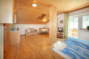 Um quarto aconchegante com cama, sofá, mesa de jantar e televisão.