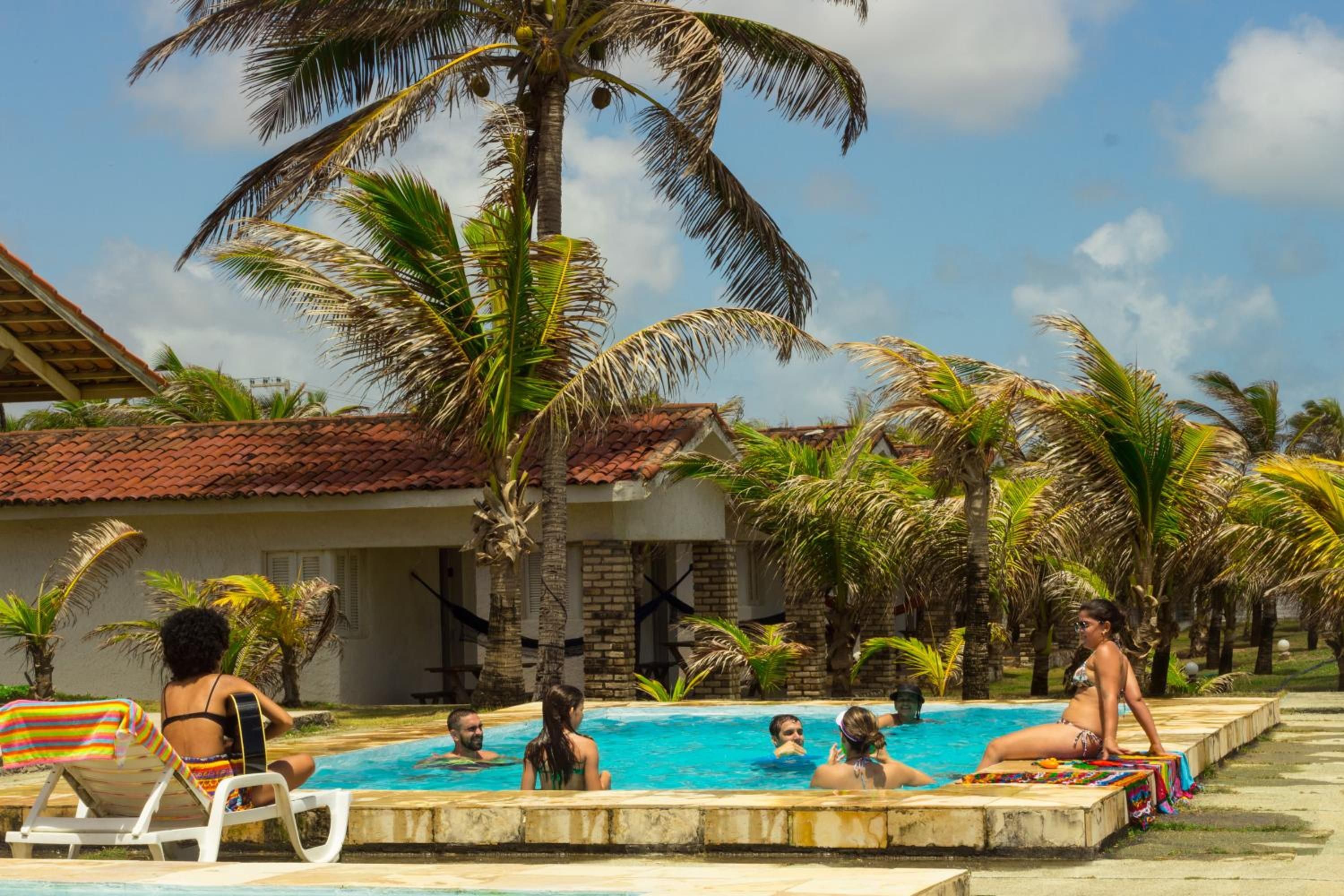 Uma área de piscina com espreguiçadeiras e palmeiras.